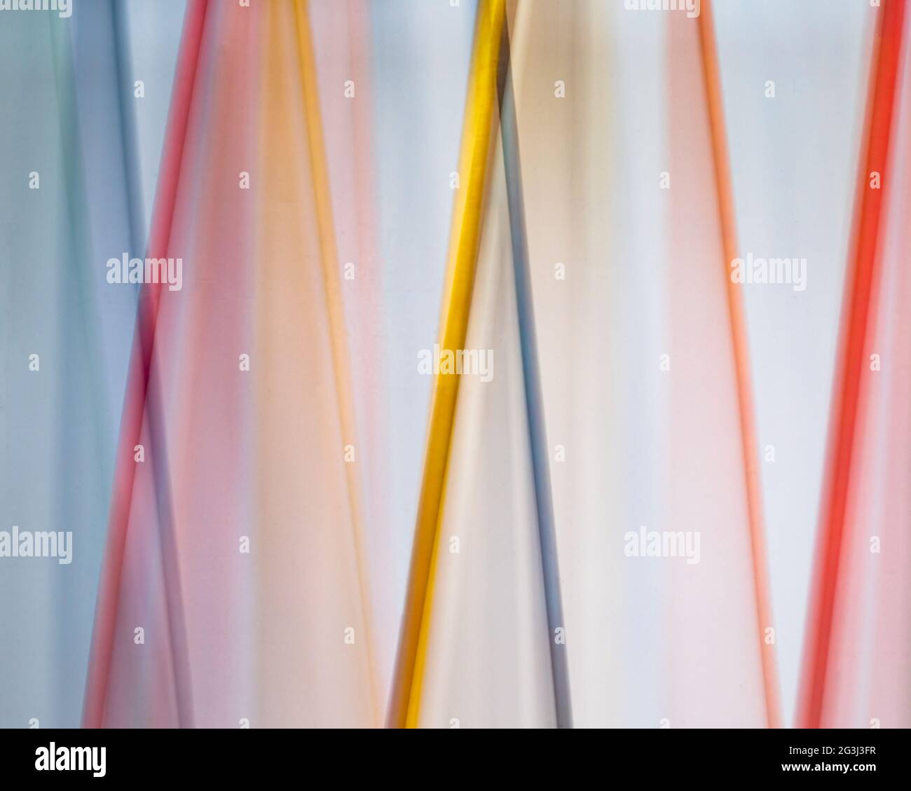 Colored dowels swing against a white background in a time lapse photo ...