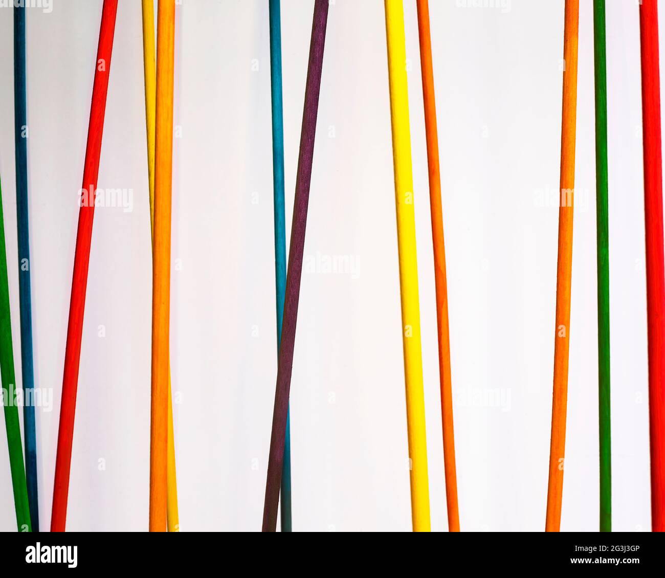 Colored dowels hang against a white background Stock Photo - Alamy