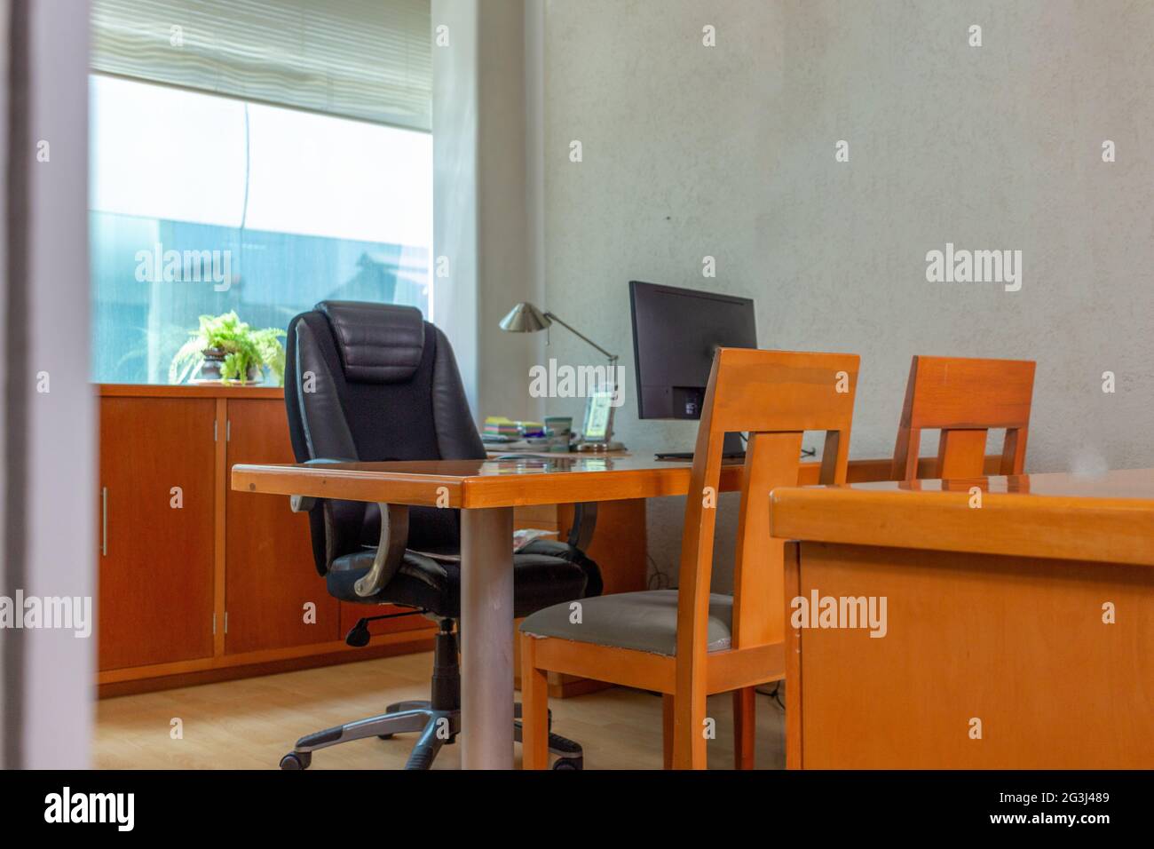 Inside view of a wooden desk with a monitor, leather chair, and a ...