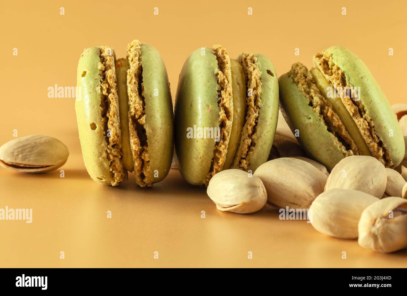 Macaroons in pistachio flavor, with pistachio seeds, against orange ...