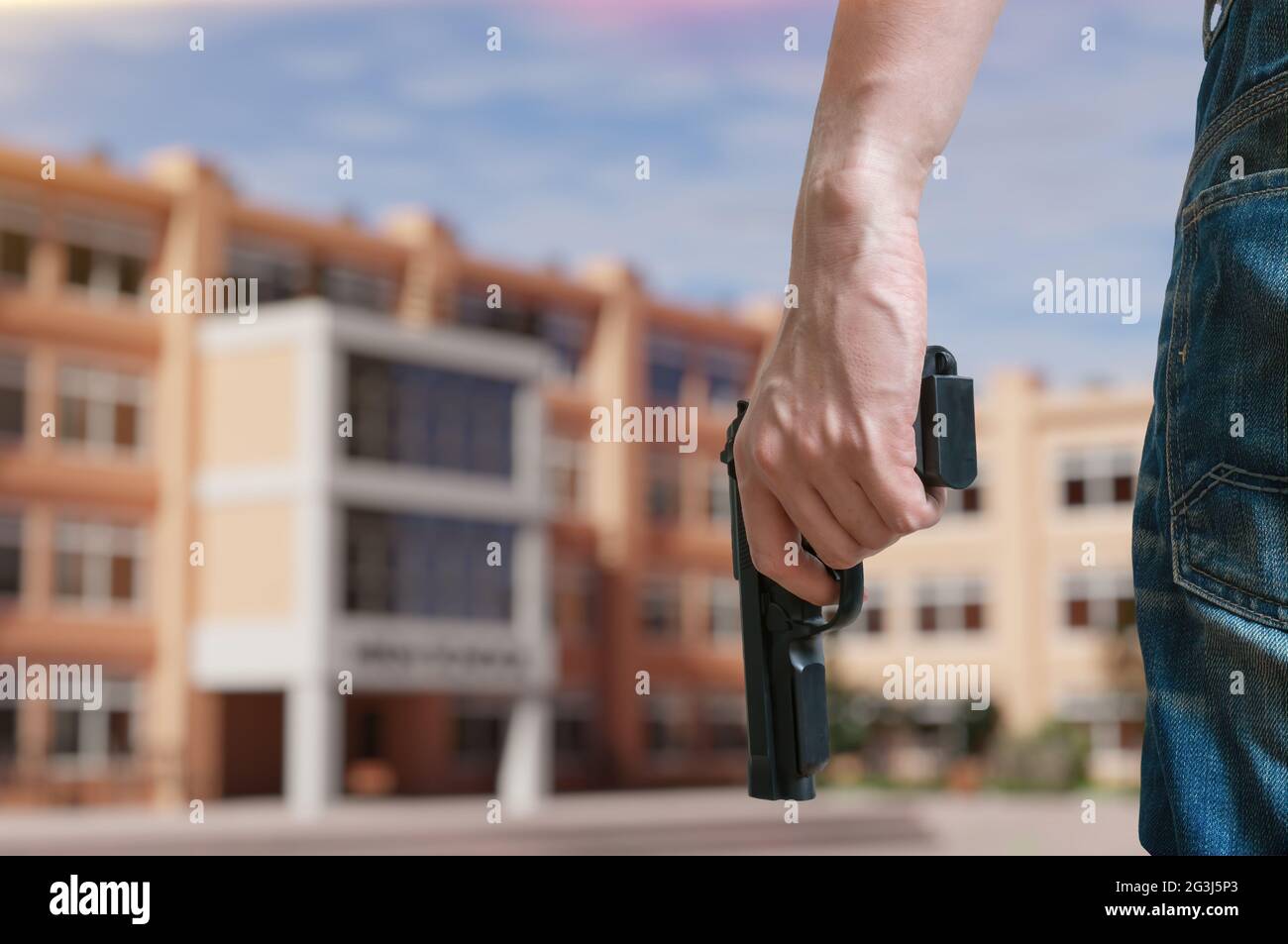 Young armed man holds pistol in hand in public place near high school ...