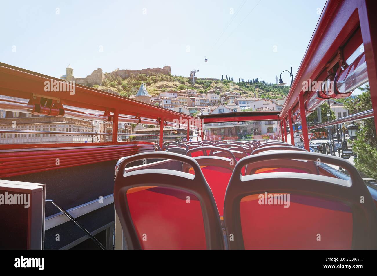 Back of red bus seats with open roof on historical city background. Bus ...