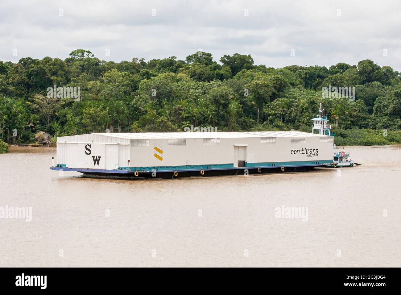 cargo vessel, passing adjacent to tropical rainforest, on River Amazon ...