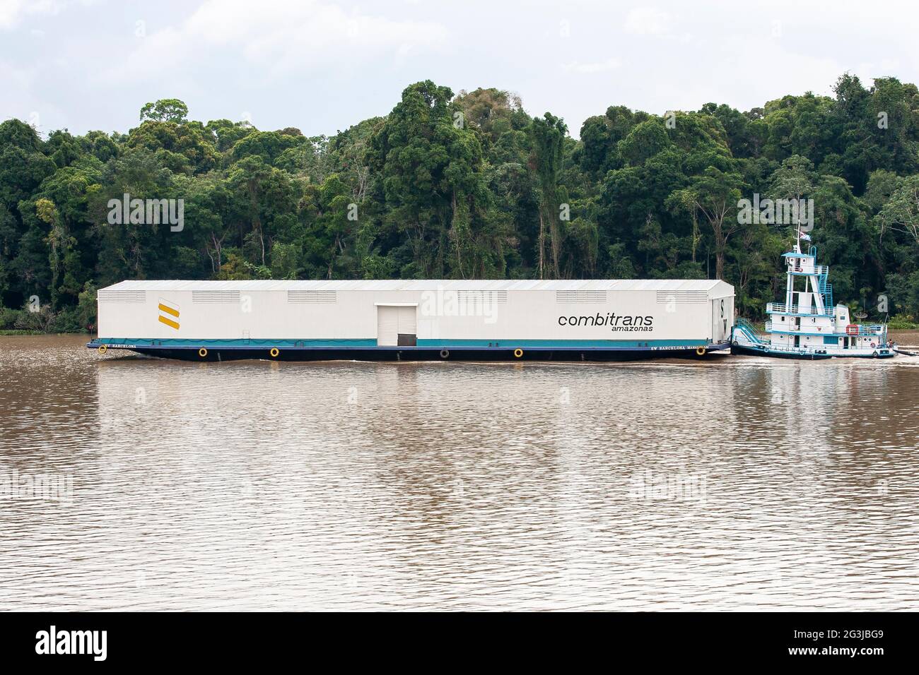 cargo vessel, passing adjacent to tropical rainforest, on River Amazon ...