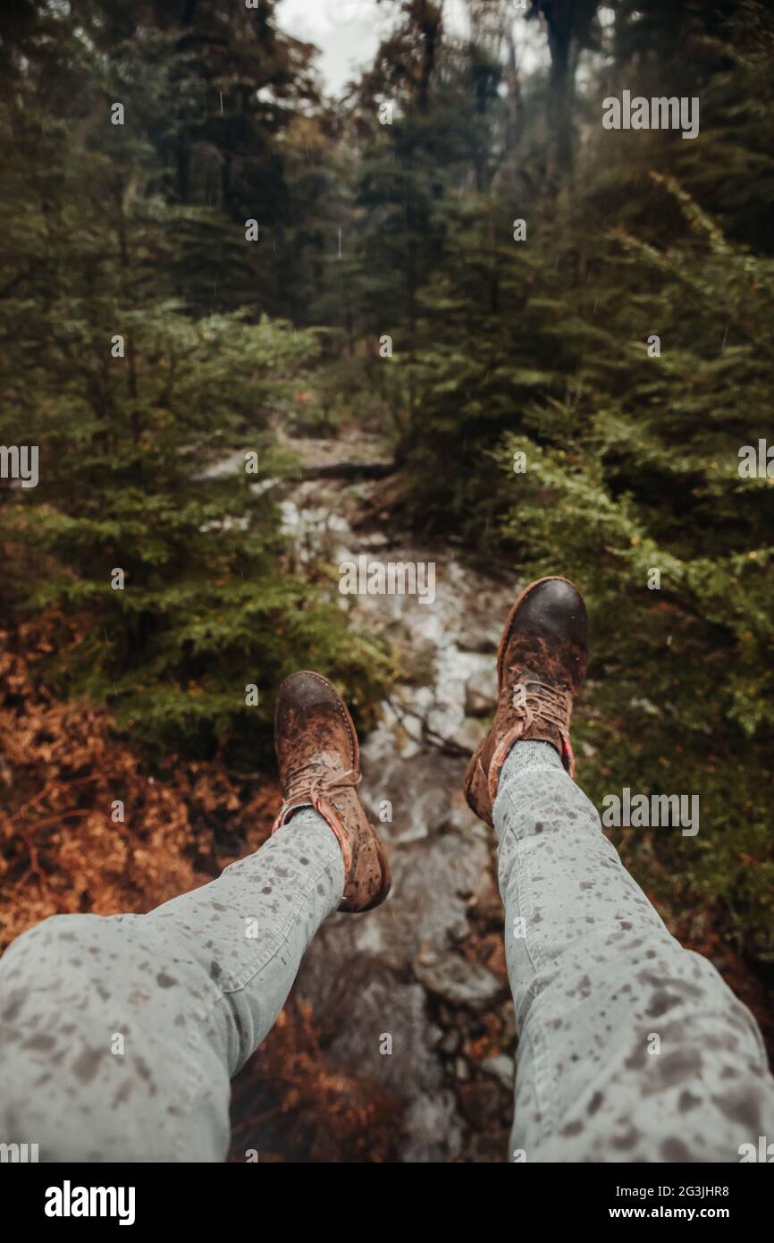 Vertical shot of male legs with a wild landscape on the background ...