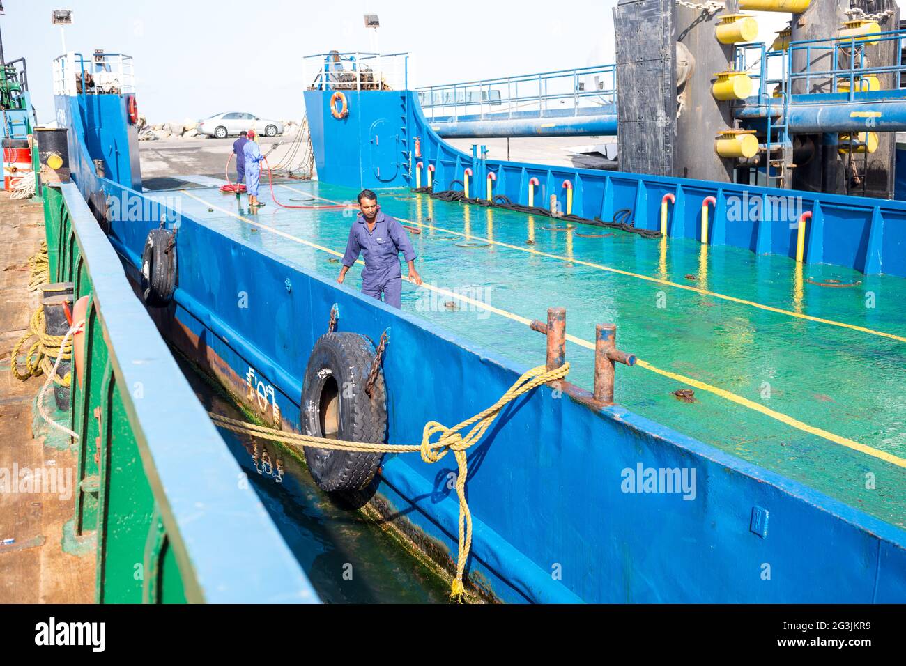 Masirah Ferry, Oman; men cleaning the deck of a local ferry which is ...