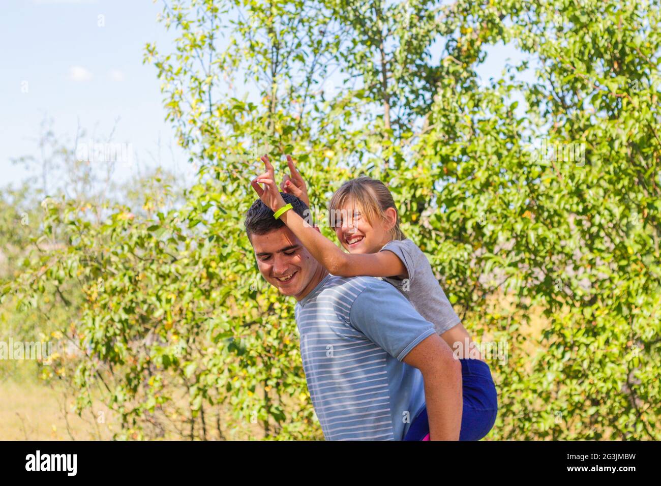 Defocused brother giving sister ride on back. Portrait of happy girl ...