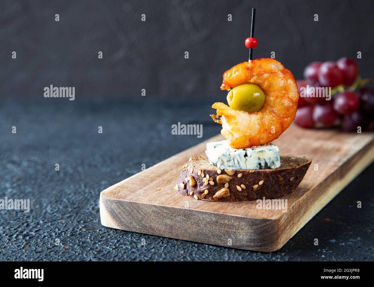 Single classic Spanish tapas lie on a wooden board. The tapas consist ...
