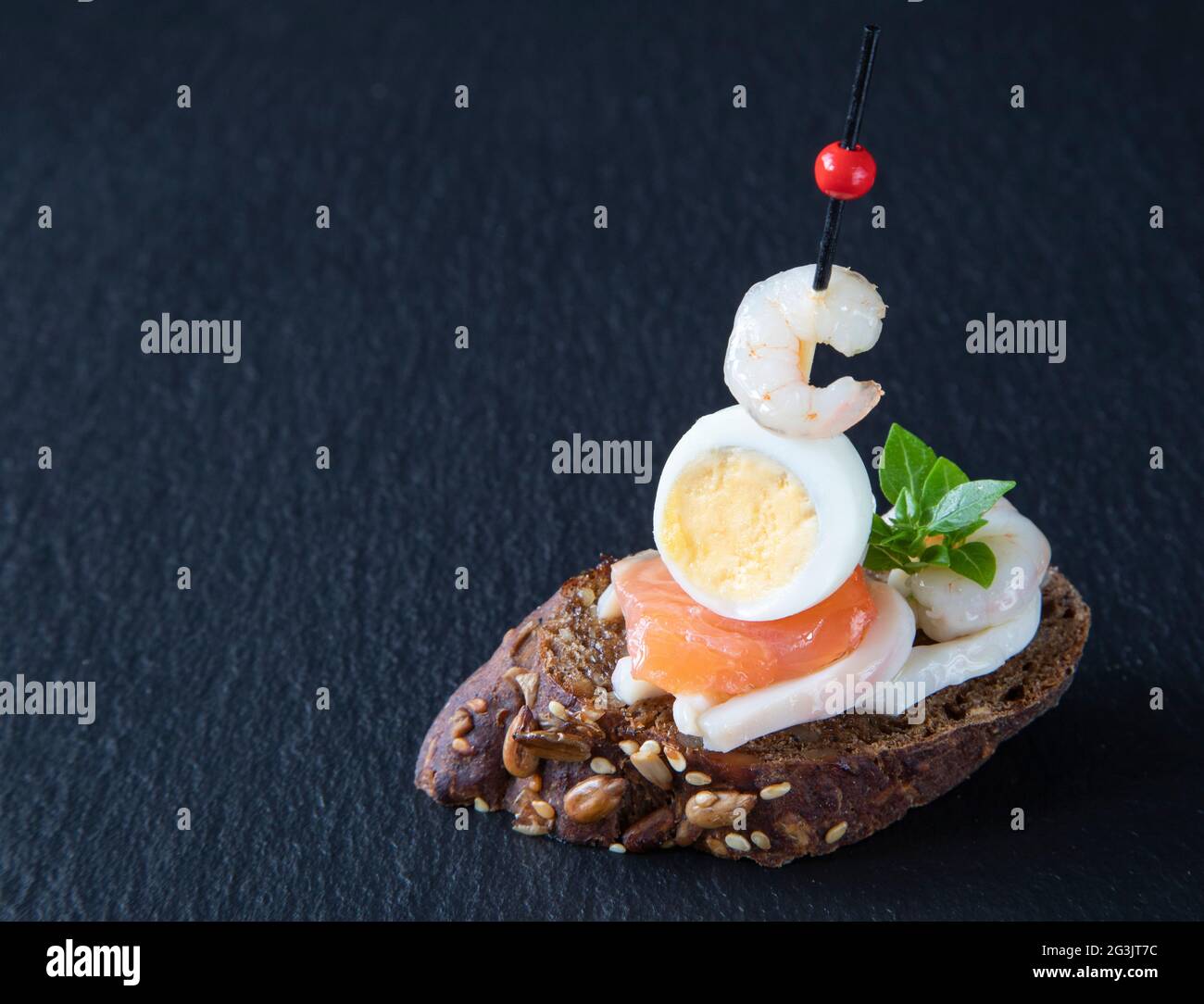 Creative traditional food - Spanish tapas on a black serving board ...