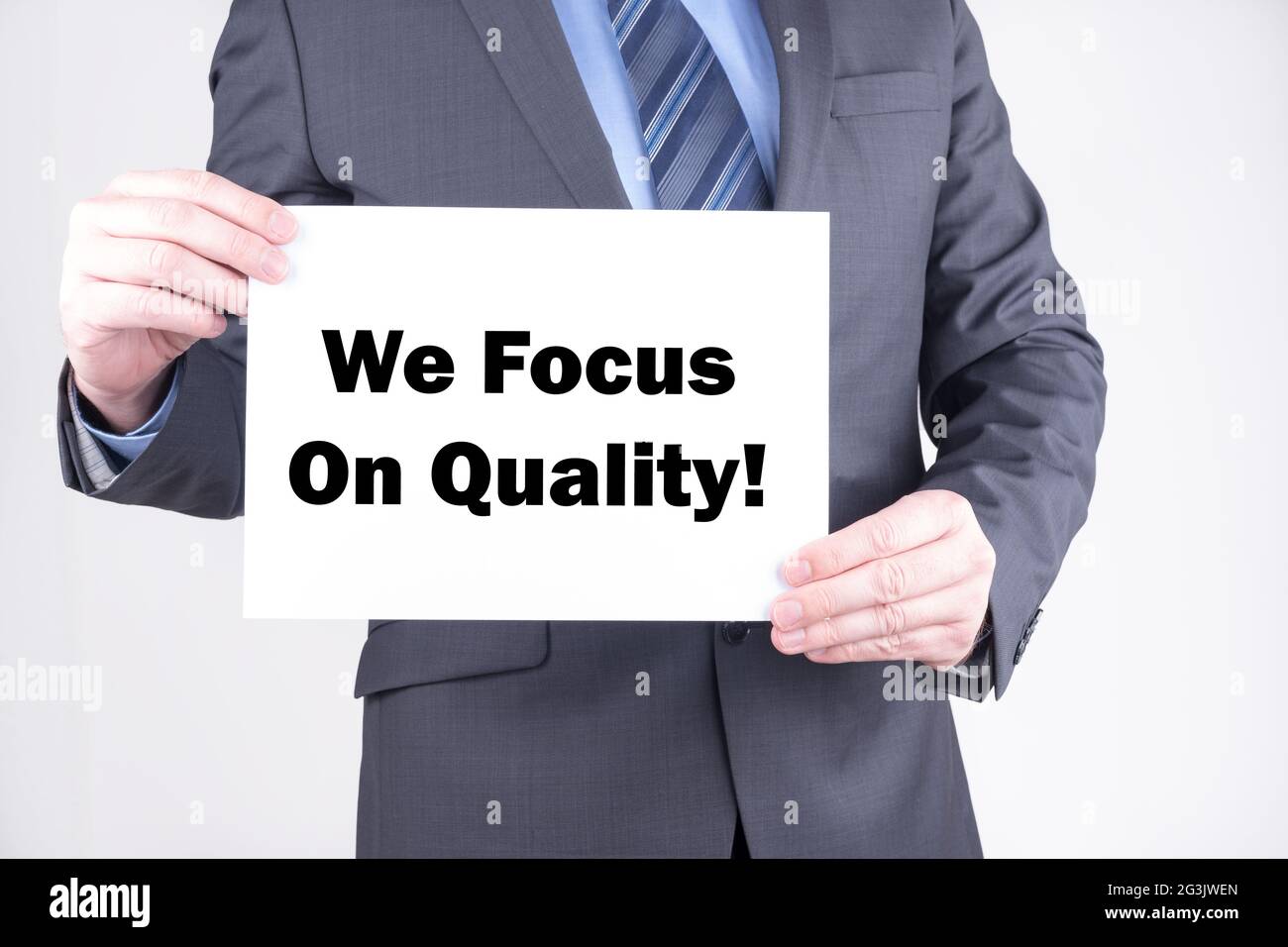 Male in suit holding a poster with text we focus on quality Stock Photo ...