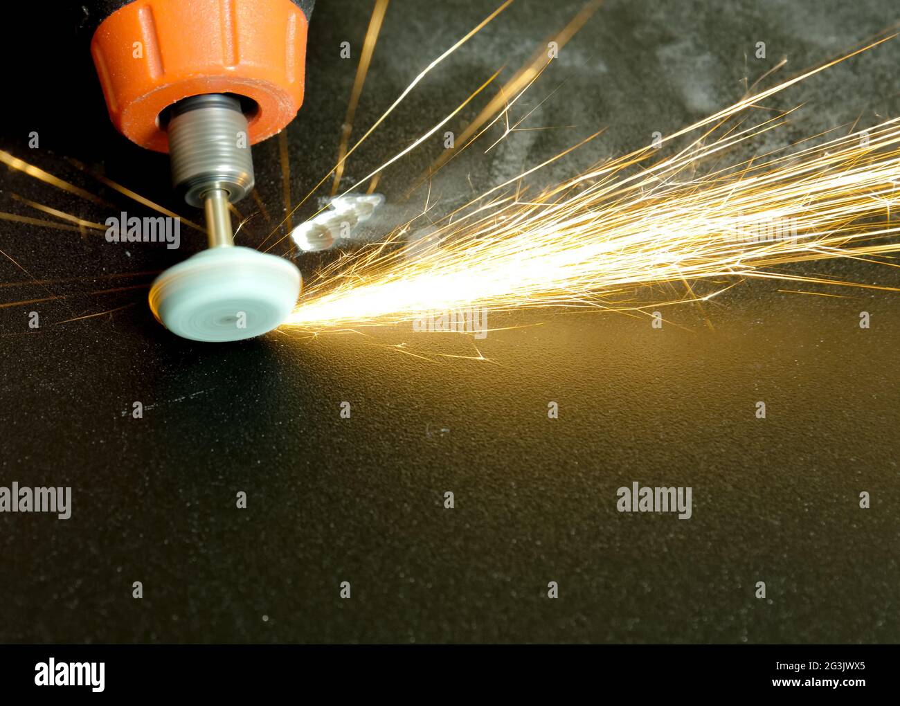 Grinding a piece of black painted metal. Sparks shoot from the grinding ...