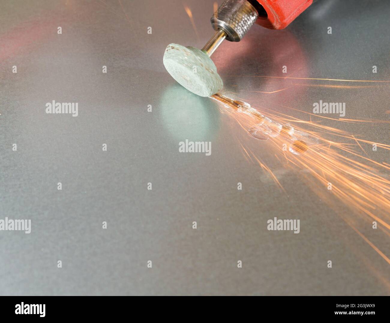 Grinding a piece of tarnished, unpainted metal.Sparks shoot from the ...