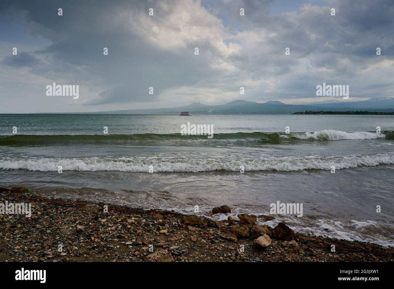 Foamy waves of Lake Sevan breaking on a beach on a gloomy day in ...