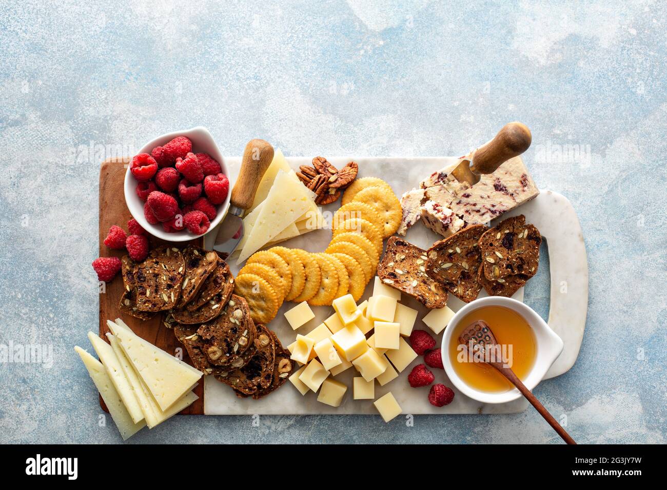 Cheese and snacks board with raspberry and crackers Stock Photo - Alamy