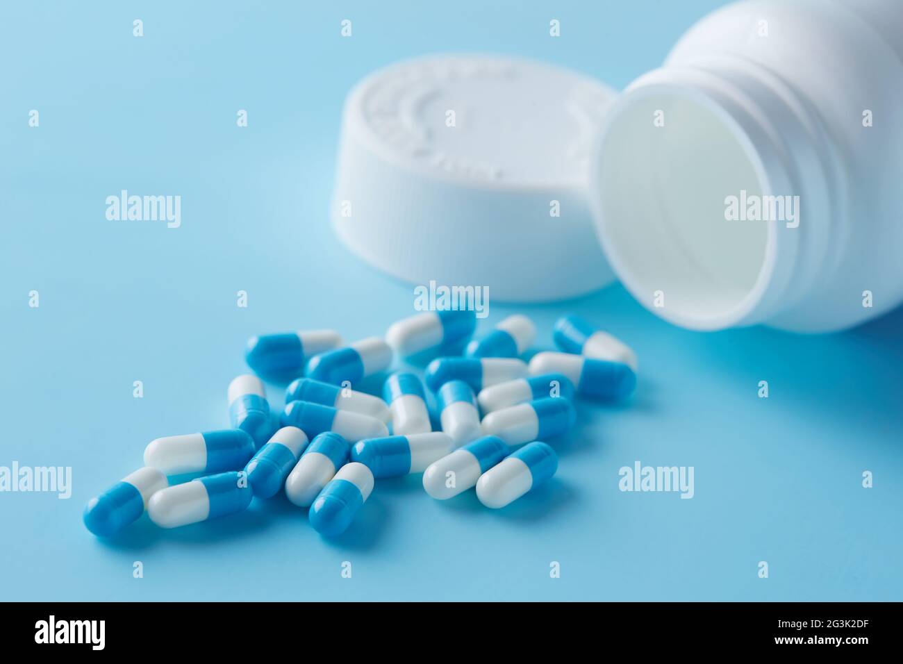 Blue and white capsules pill spread on blue background with shadow ...