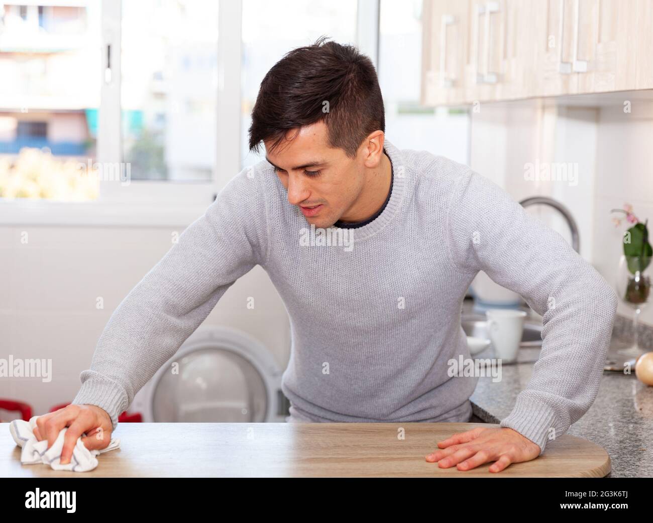 Man wipes a kitchen table with a rag Stock Photo - Alamy