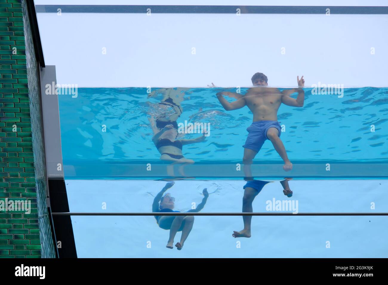 London, UK A swimmer giving peace signs comes to the side of the Sky ...