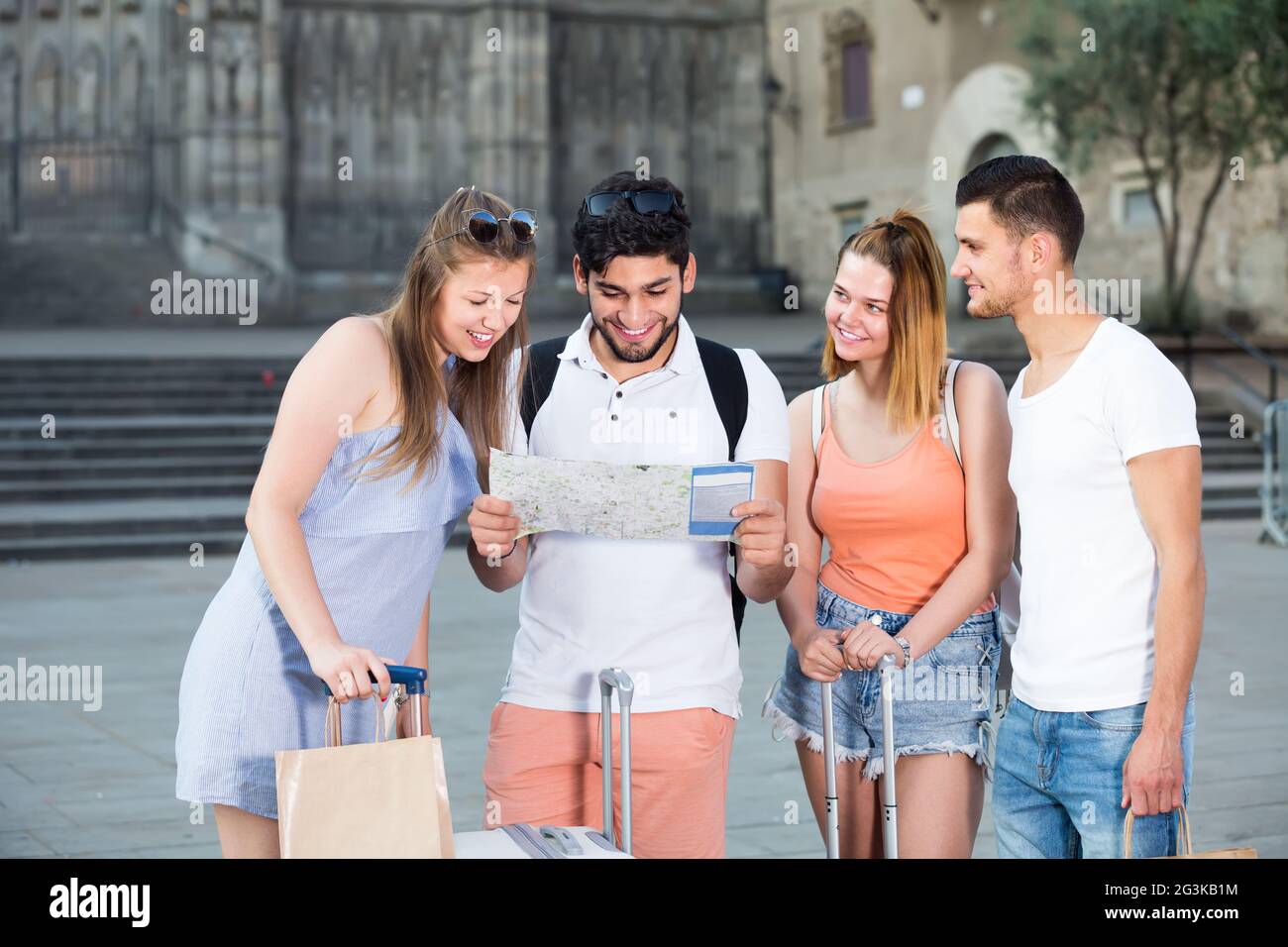 four traveling young people searching for direction using paper map in ...