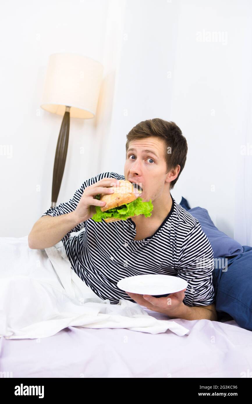 Single man eating in bed Stock Photo - Alamy