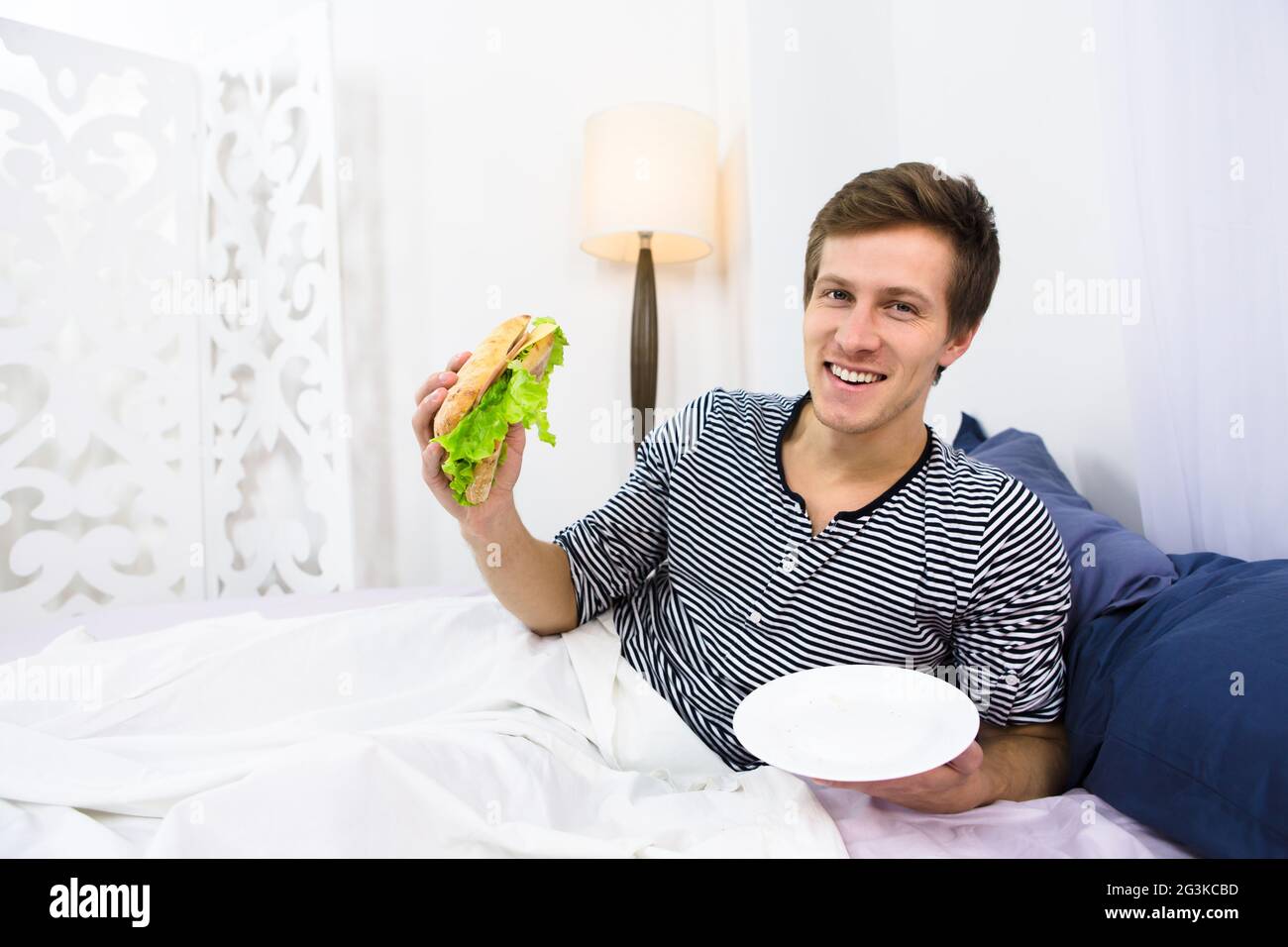 Single man eating in bed Stock Photo - Alamy