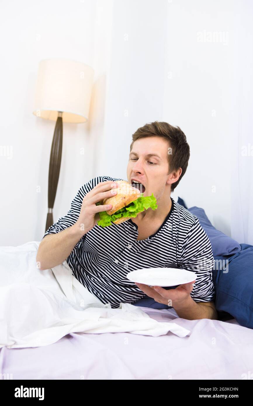 Single man eating in bed Stock Photo - Alamy