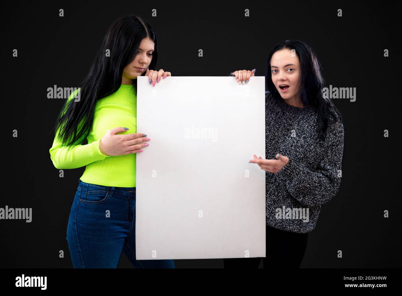 two attractive funny young women with a white blank poster, isolated on ...