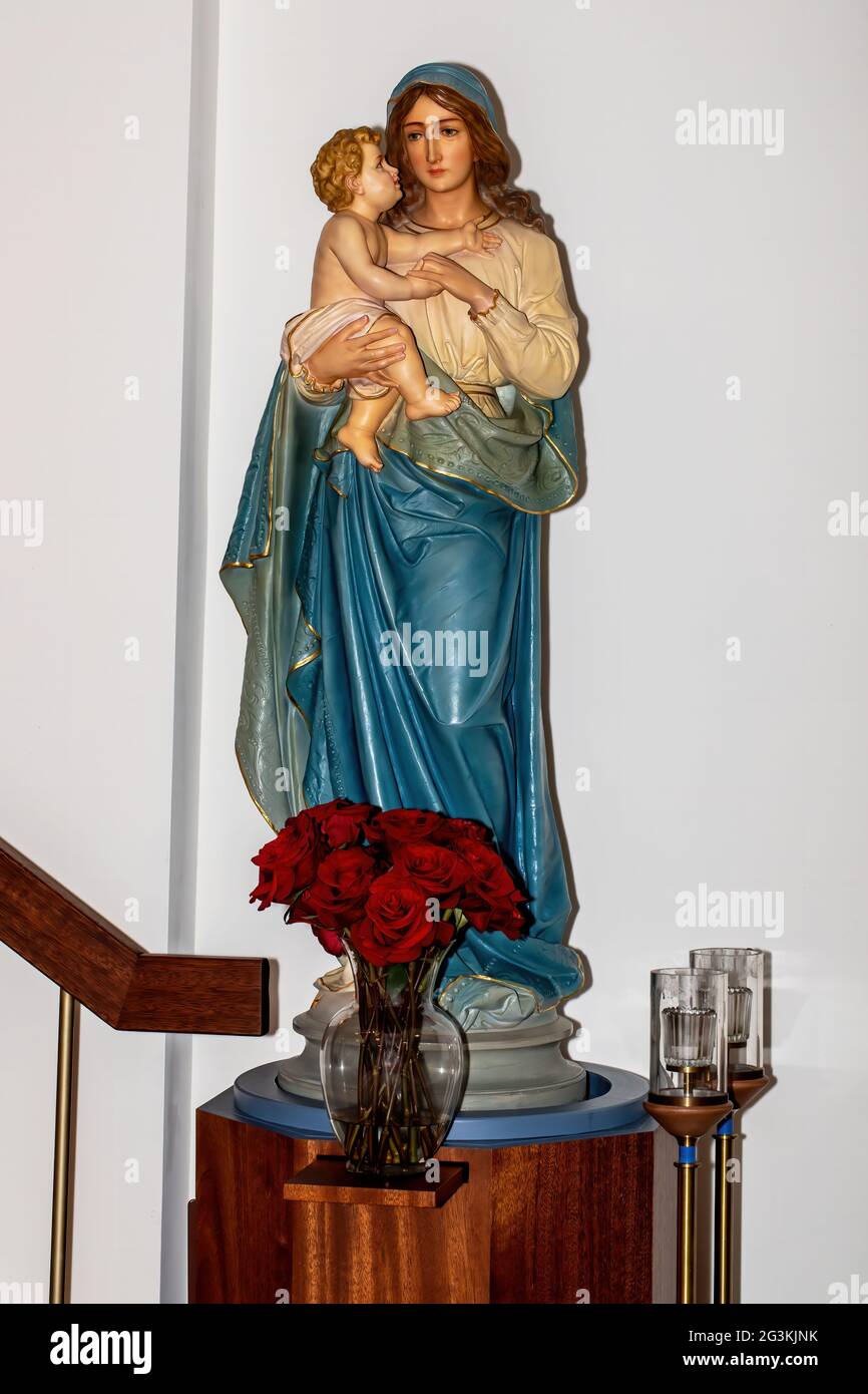 Statue of Mary and Baby Jesus with red roses in honor of her Queenship ...