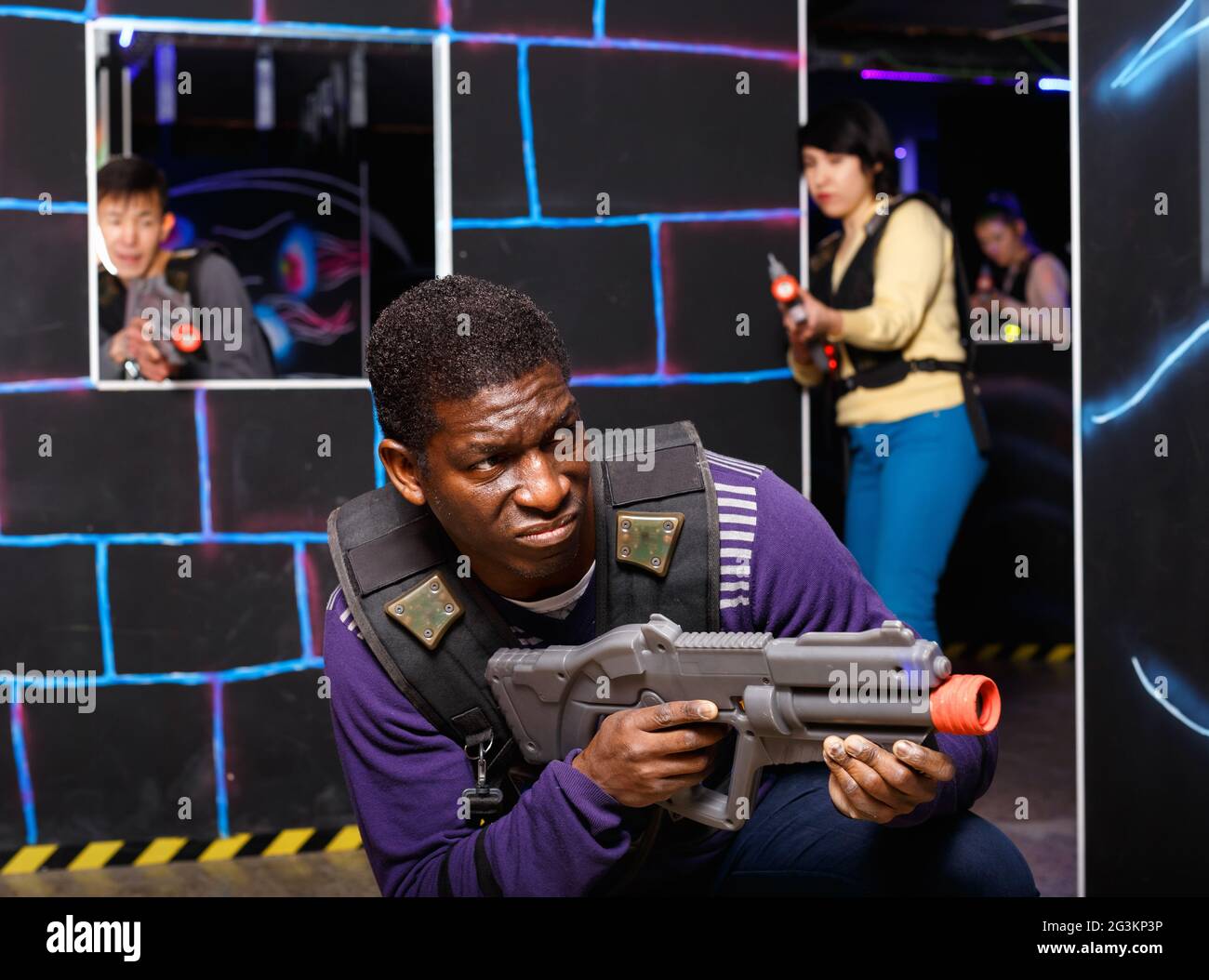 Portrait of cheerful African-American with laser gun having fun on dark ...