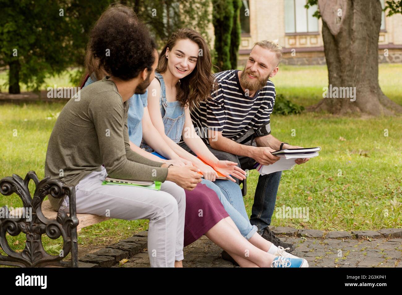Young students sitting on bench studying Stock Photo - Alamy