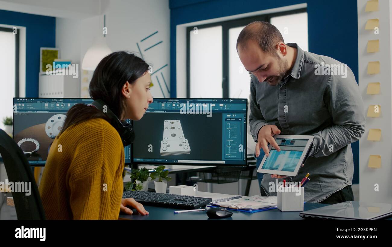 Industrial designer discussing with colleague holding tablet with in ...