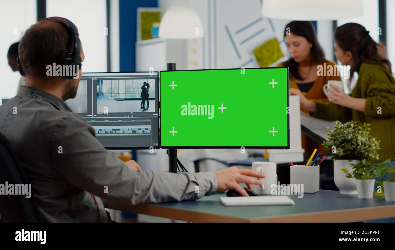 Man videographer with headset editing movie in post production software ...