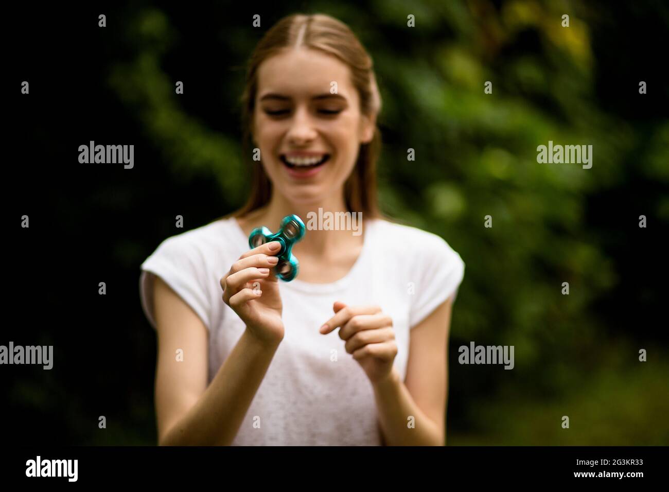 Girl playing with fidget spinner smiling Stock Photo - Alamy