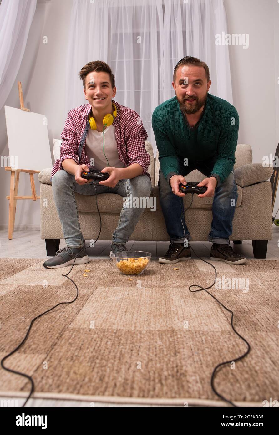 Happy son and father playing video game together Stock Photo - Alamy