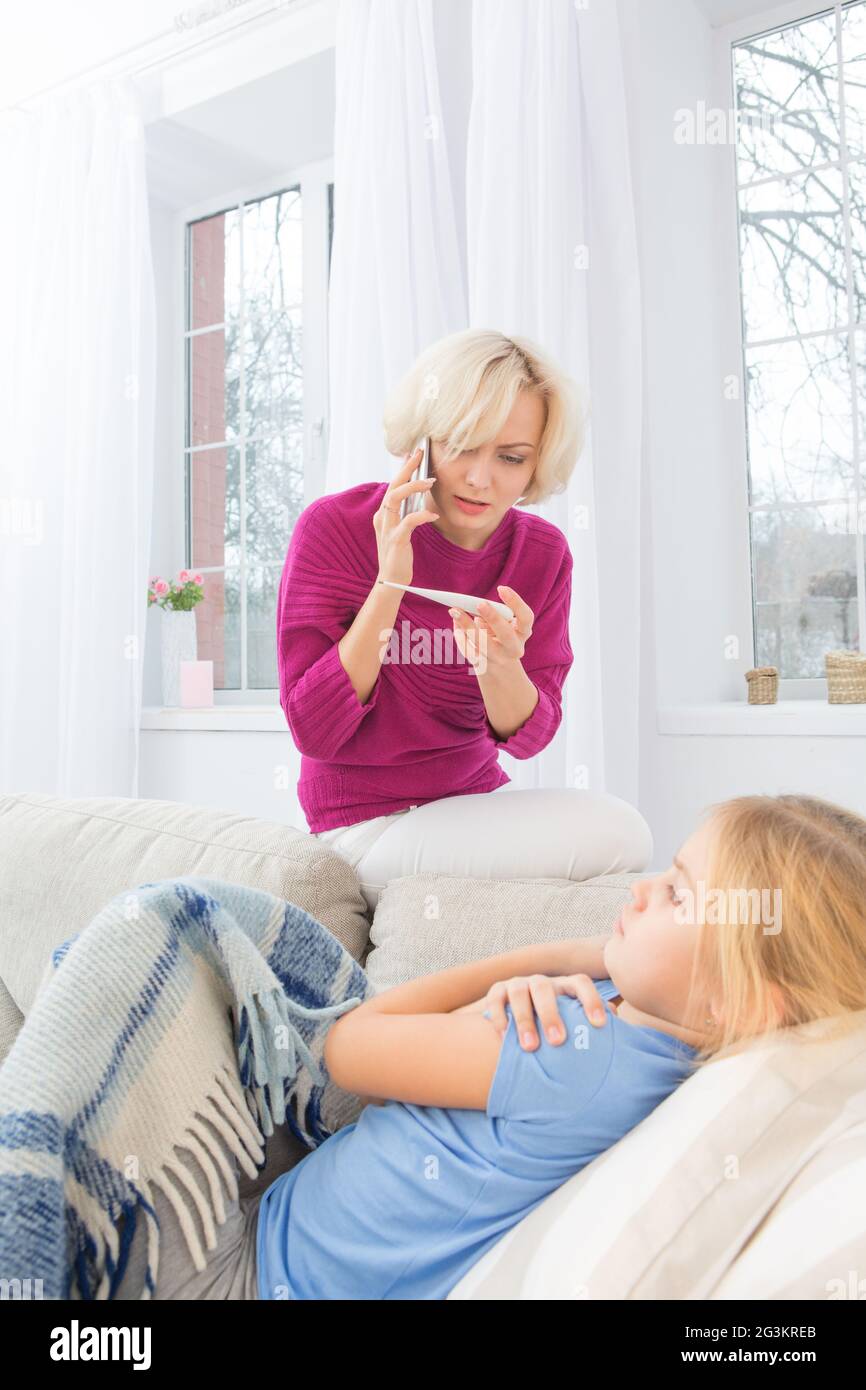 Worried mom calling doctor holding thermometer in hand Stock Photo - Alamy