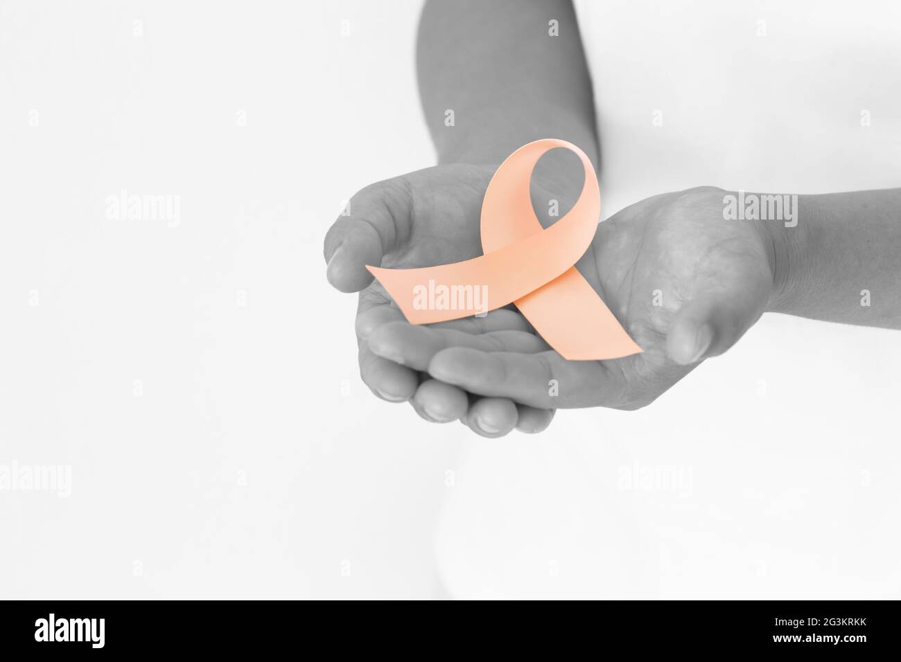Hand holding Peach color ribbon curl on white fabric background with ...
