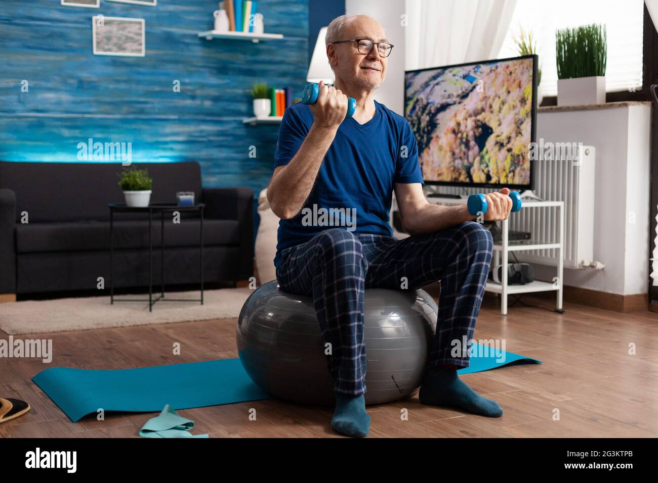 Senior man holding dumbbells doing arms exercise streching body muscles ...