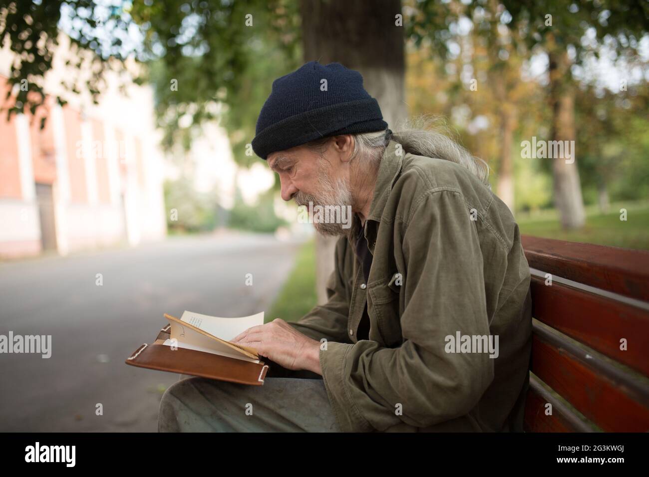 Side view of old homeless man with long grey hair reading a book Stock ...