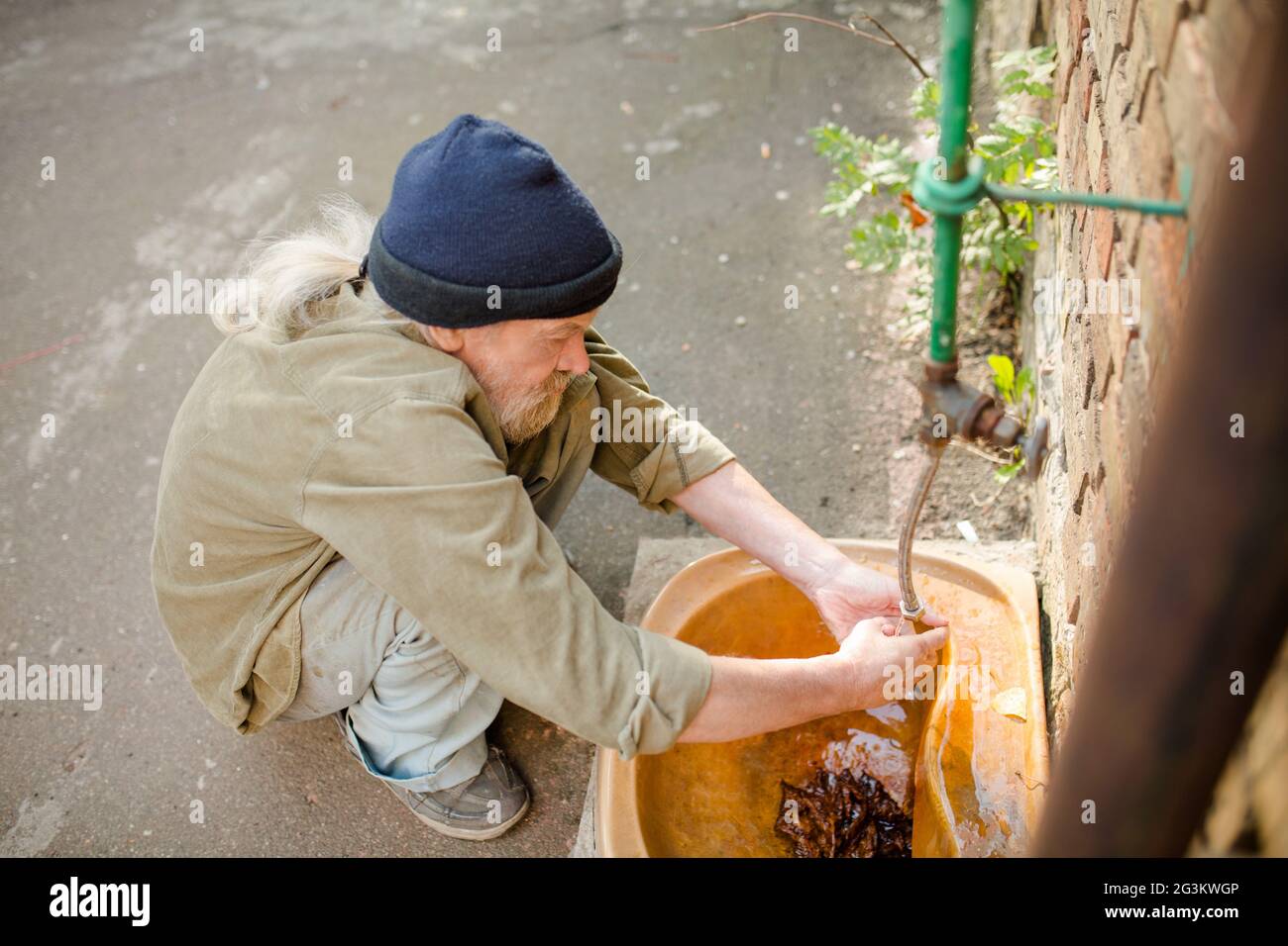 Side view of homeless man washing hands in old sink in the street Stock ...