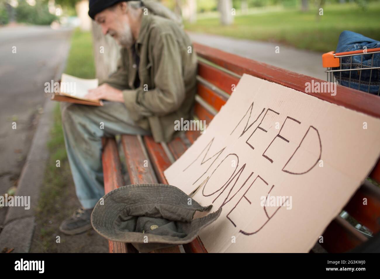On front view board with sign need money and hat with some coins ...