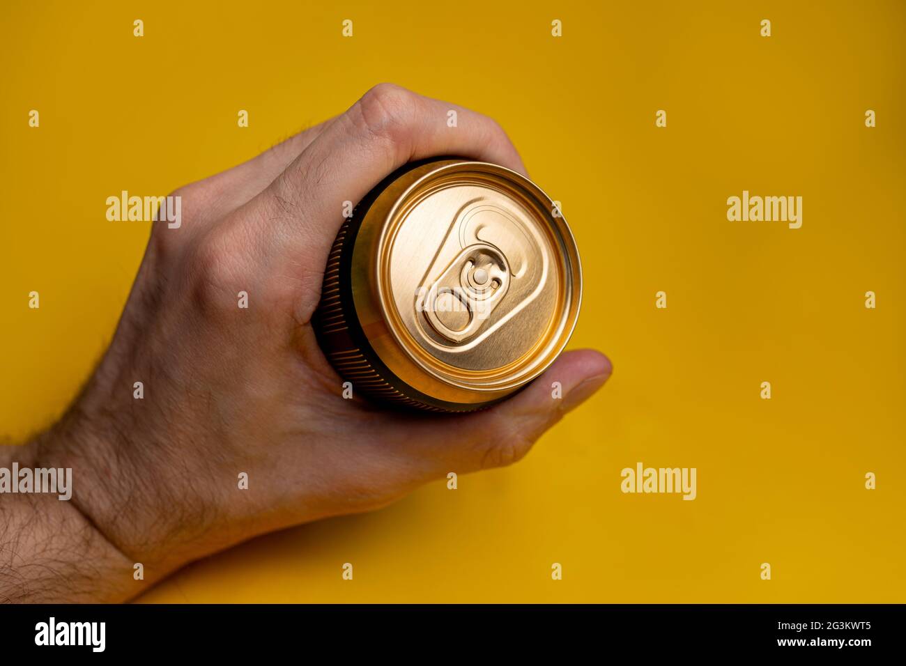 metal beer can in a man's hand on a yellow background Stock Photo - Alamy