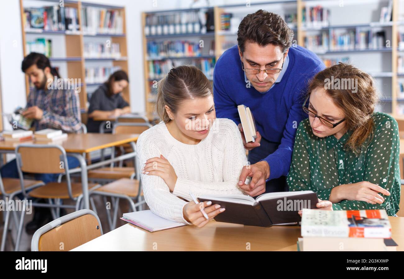 Female students working with professor in library Stock Photo - Alamy