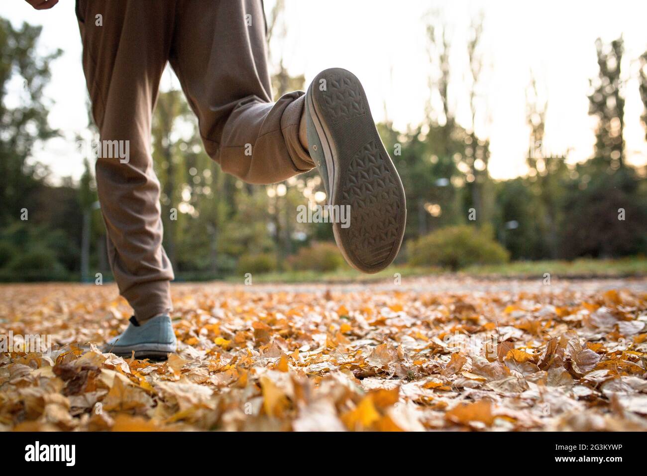 Close up view of man running on dried autumn leaves Stock Photo - Alamy