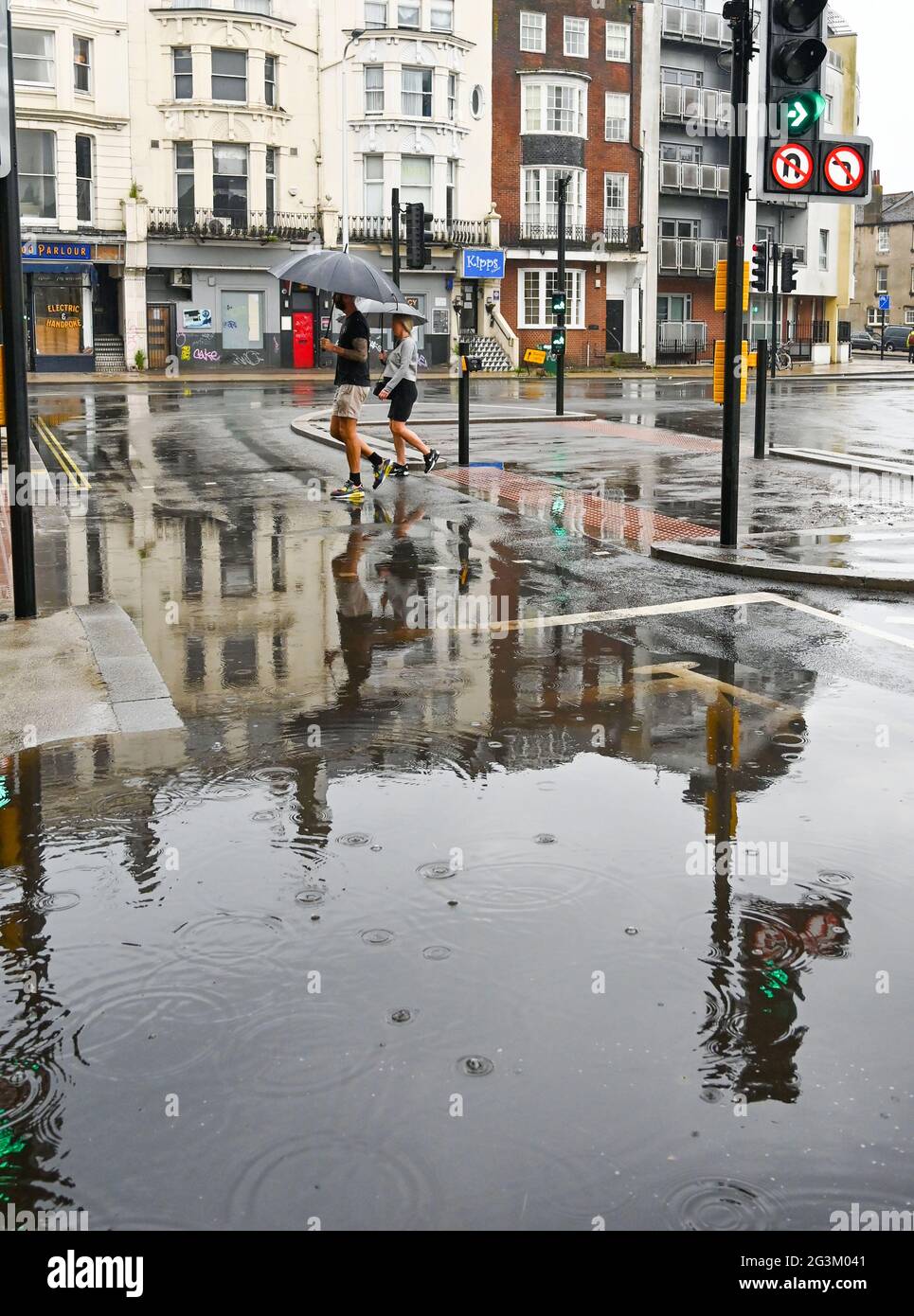 Brighton UK 17th June 2021 - Walkers cross the road by floodwater at ...