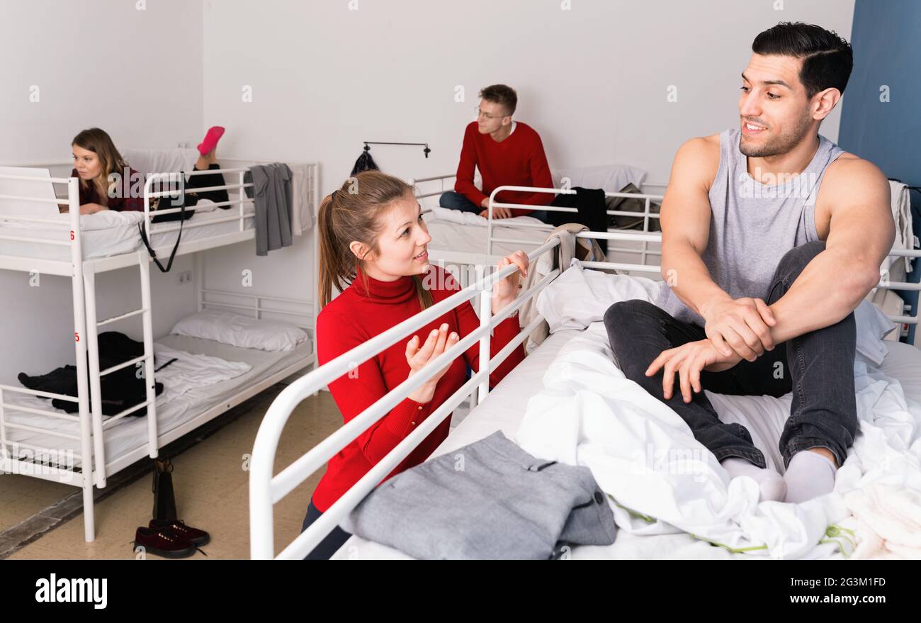 Attractive girl talking to smiling man who sitting on top bunk of bunk ...