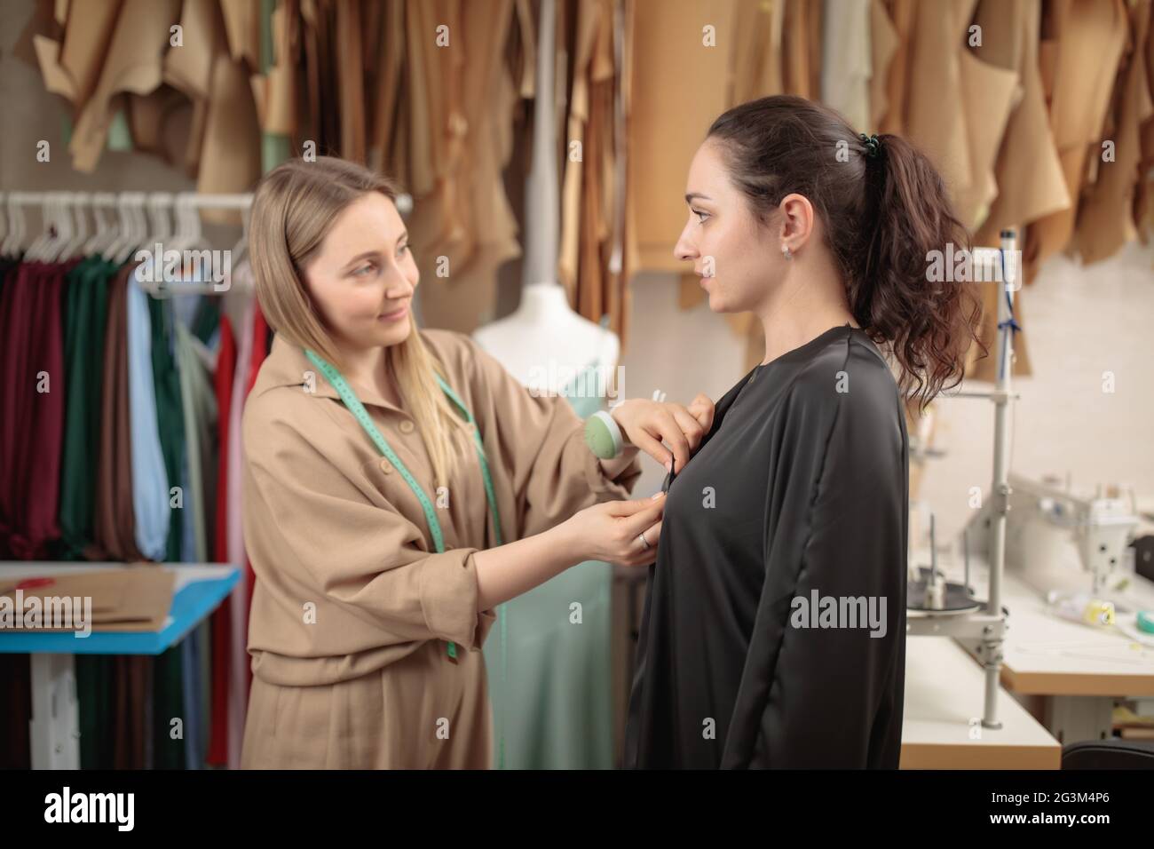 dressmaker at work making measures of client. The model came to try on ...