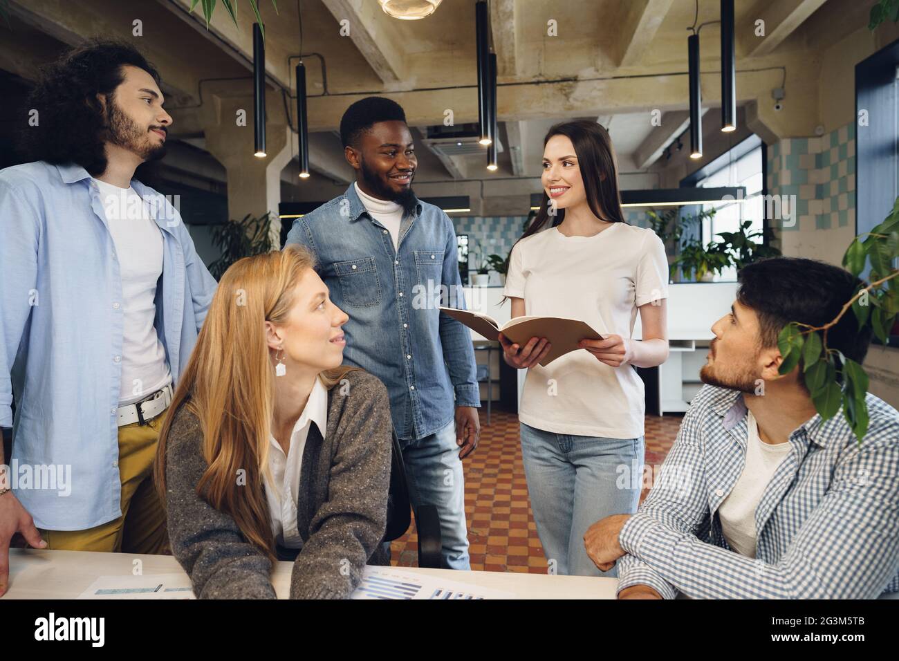 Group of young business people discussing documents during meeting in ...