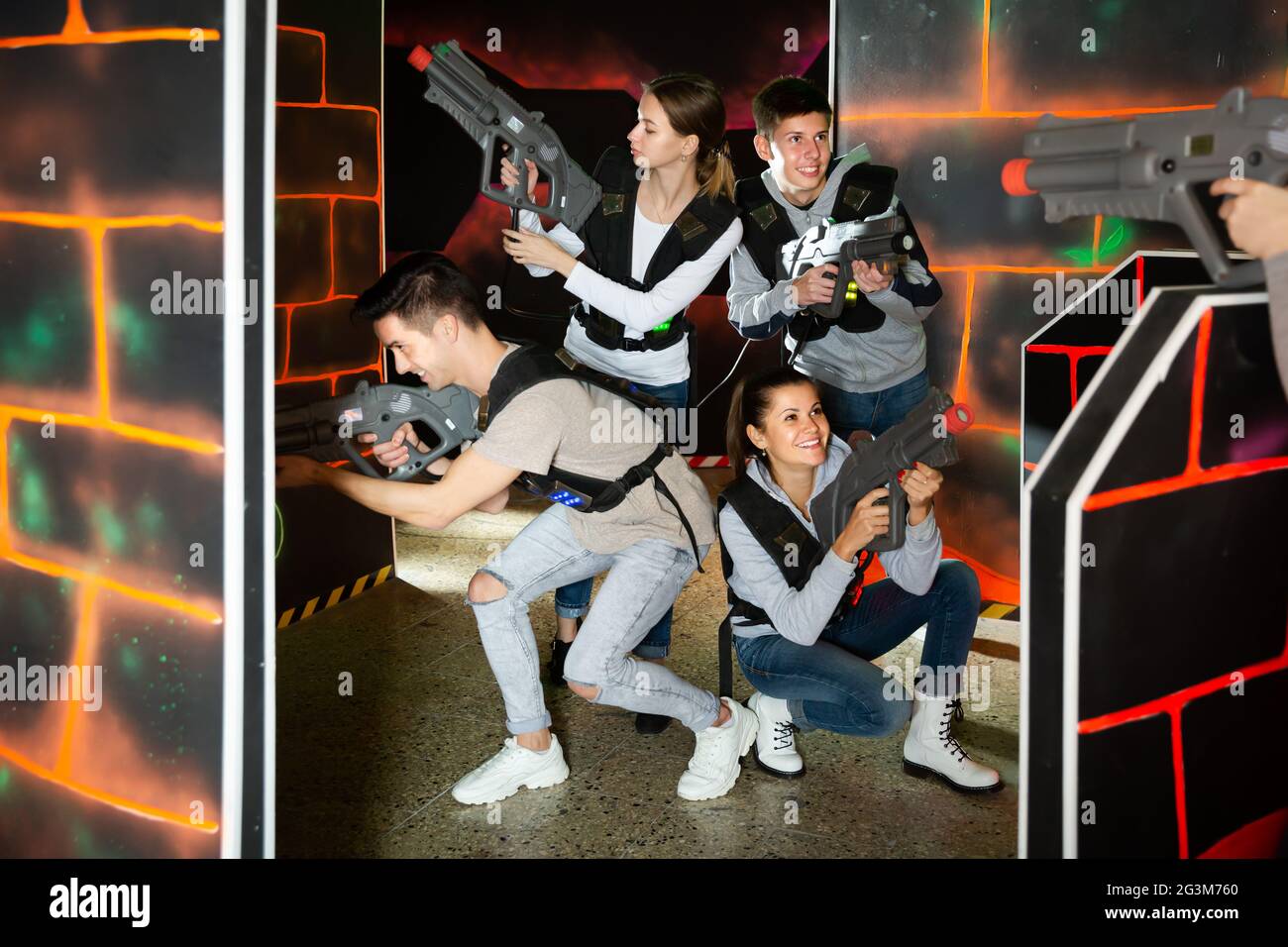 Young people aiming laser guns at other players Stock Photo - Alamy