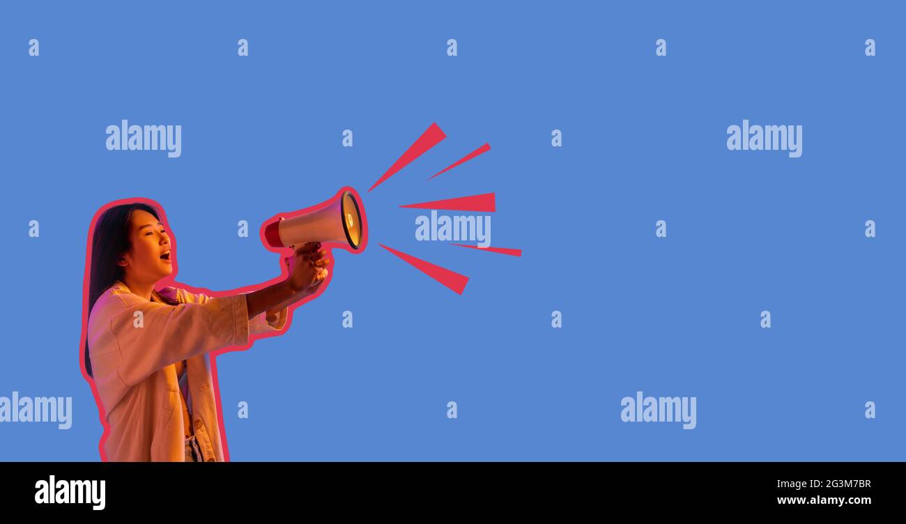 Portrait of young woman with megaphone on blue studio background in ...