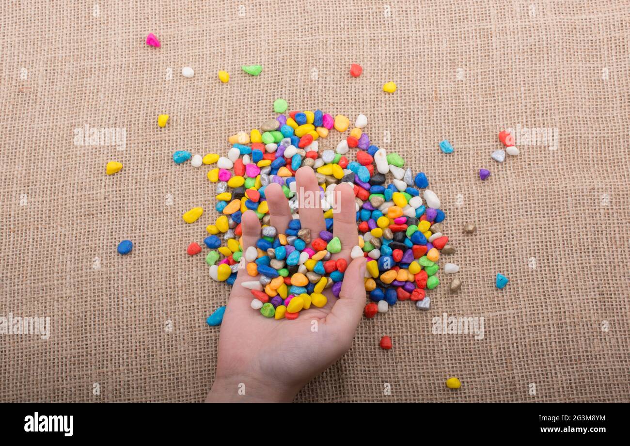 Colorful little pebbles in hand and on ground Stock Photo - Alamy