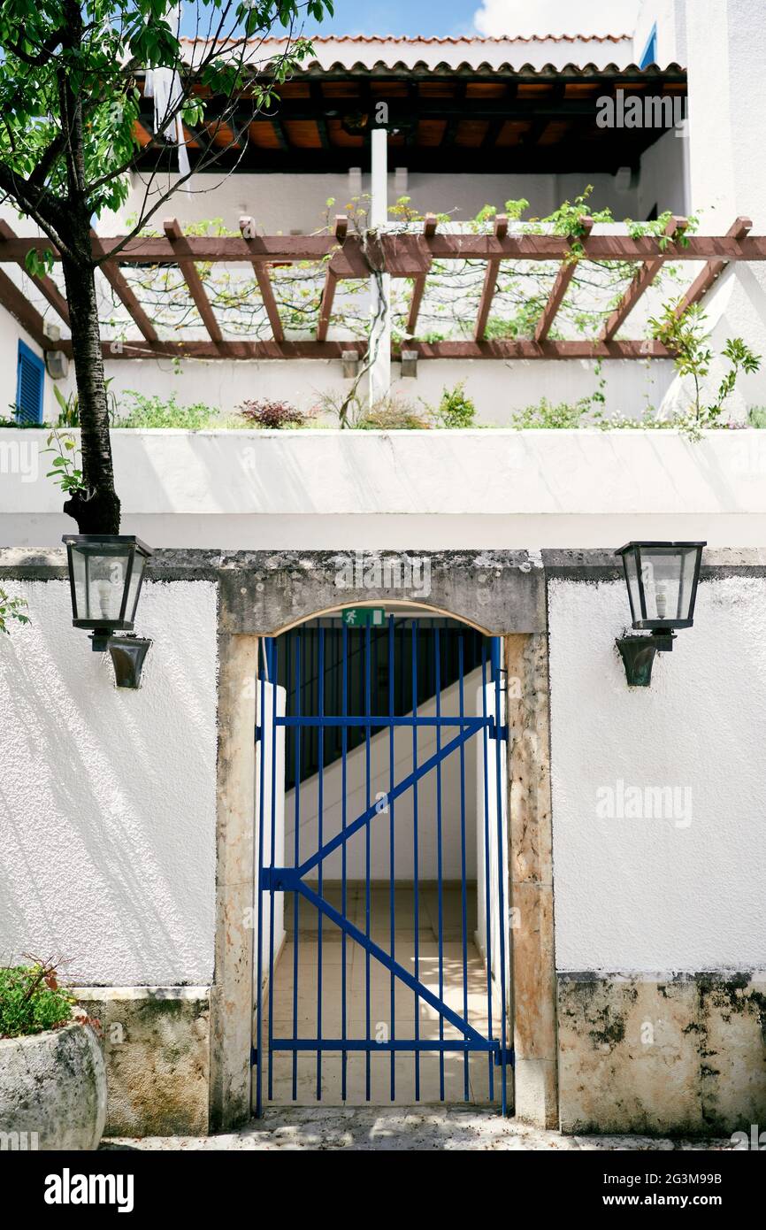 Stone fence with lattice gates near the house with a balcony, tree and ...